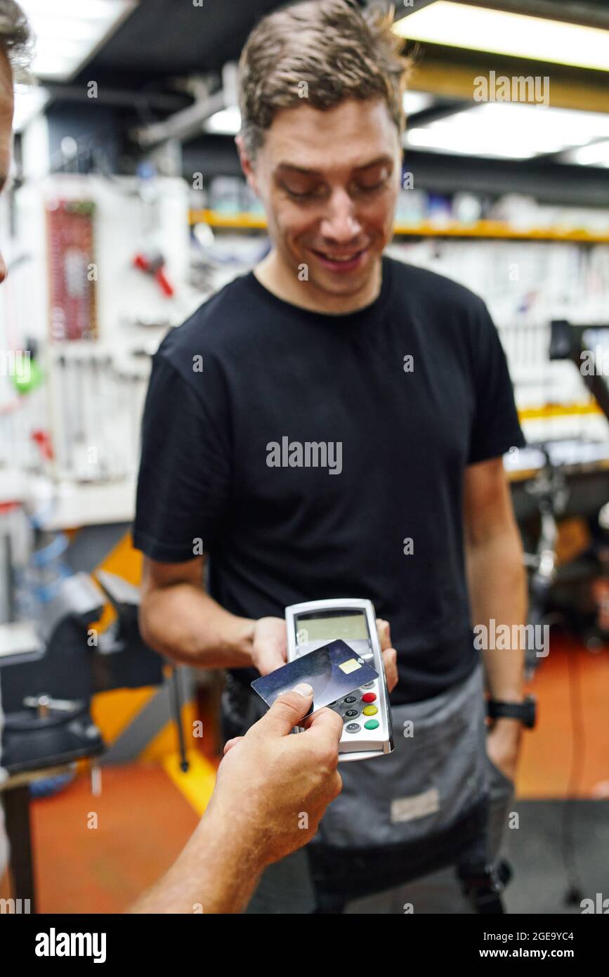 Crop customer putting credit card over contactless terminal to pay to ...