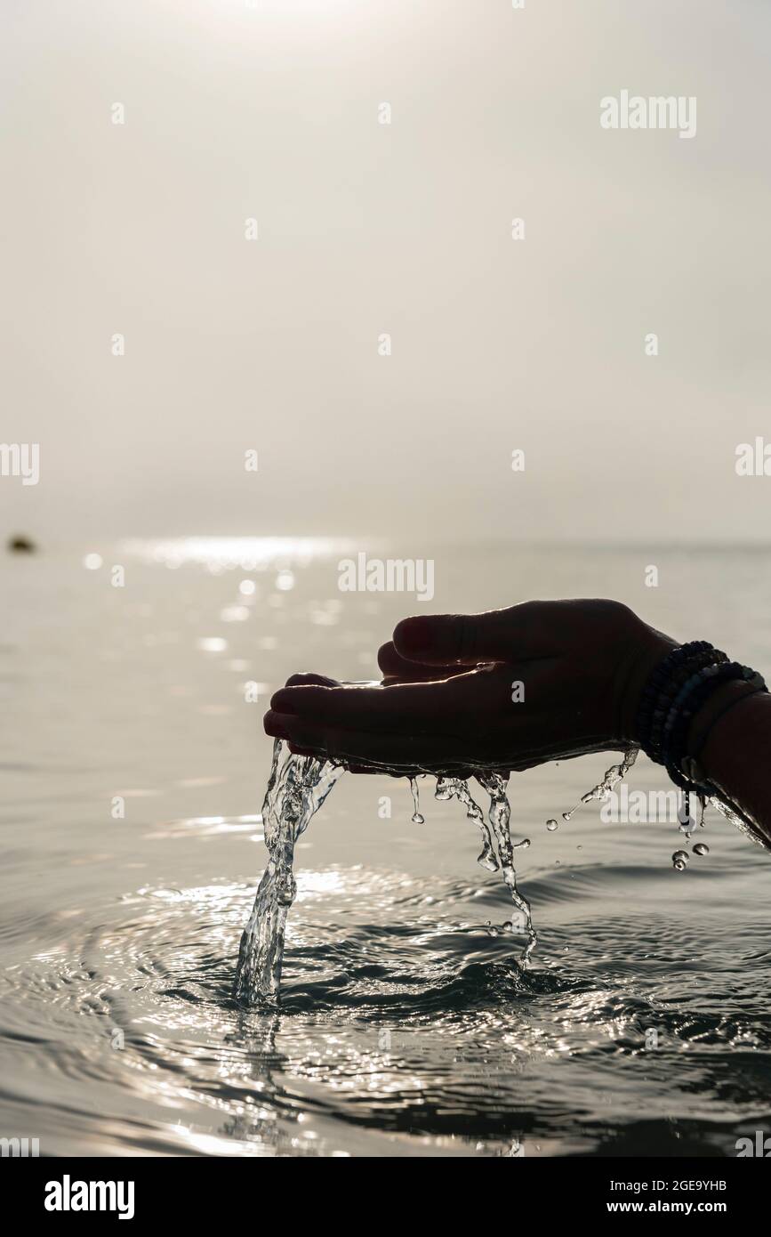 Crop faceless female with handful of water in wet hands in sea in ...
