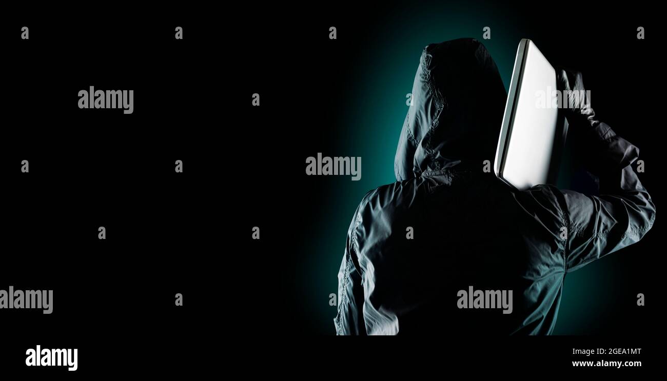 Hacker with a laptop on his shoulder on a dark background ...