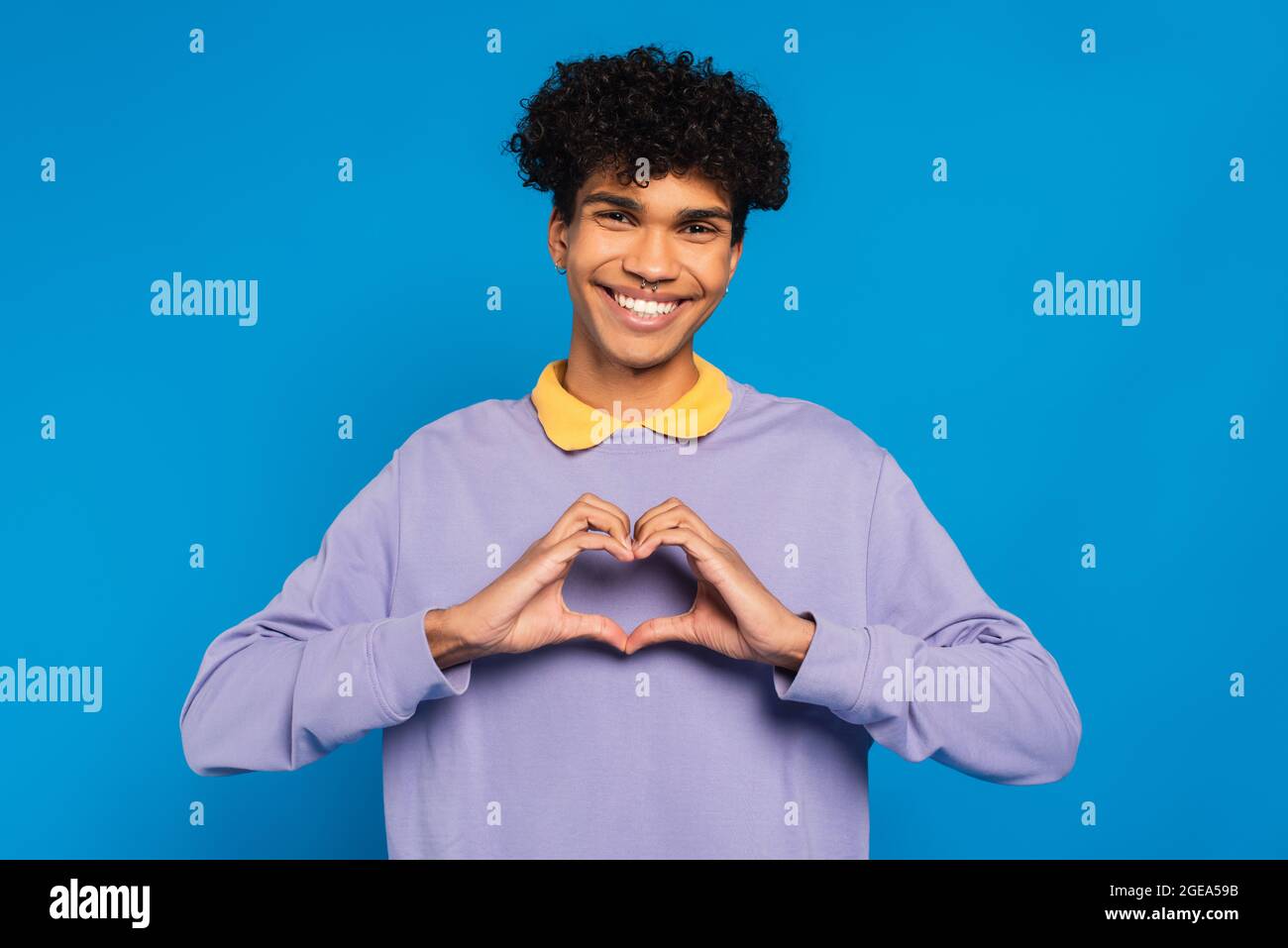 smiling african american man in purple pullover showing heart sign with ...