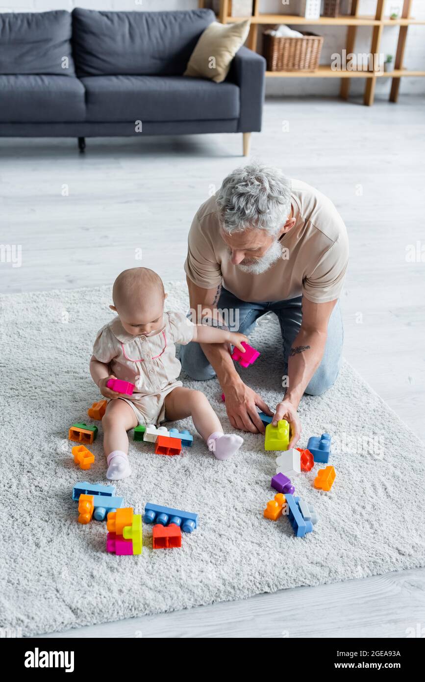 High angle view of toddler kid holding building blocks near father on ...
