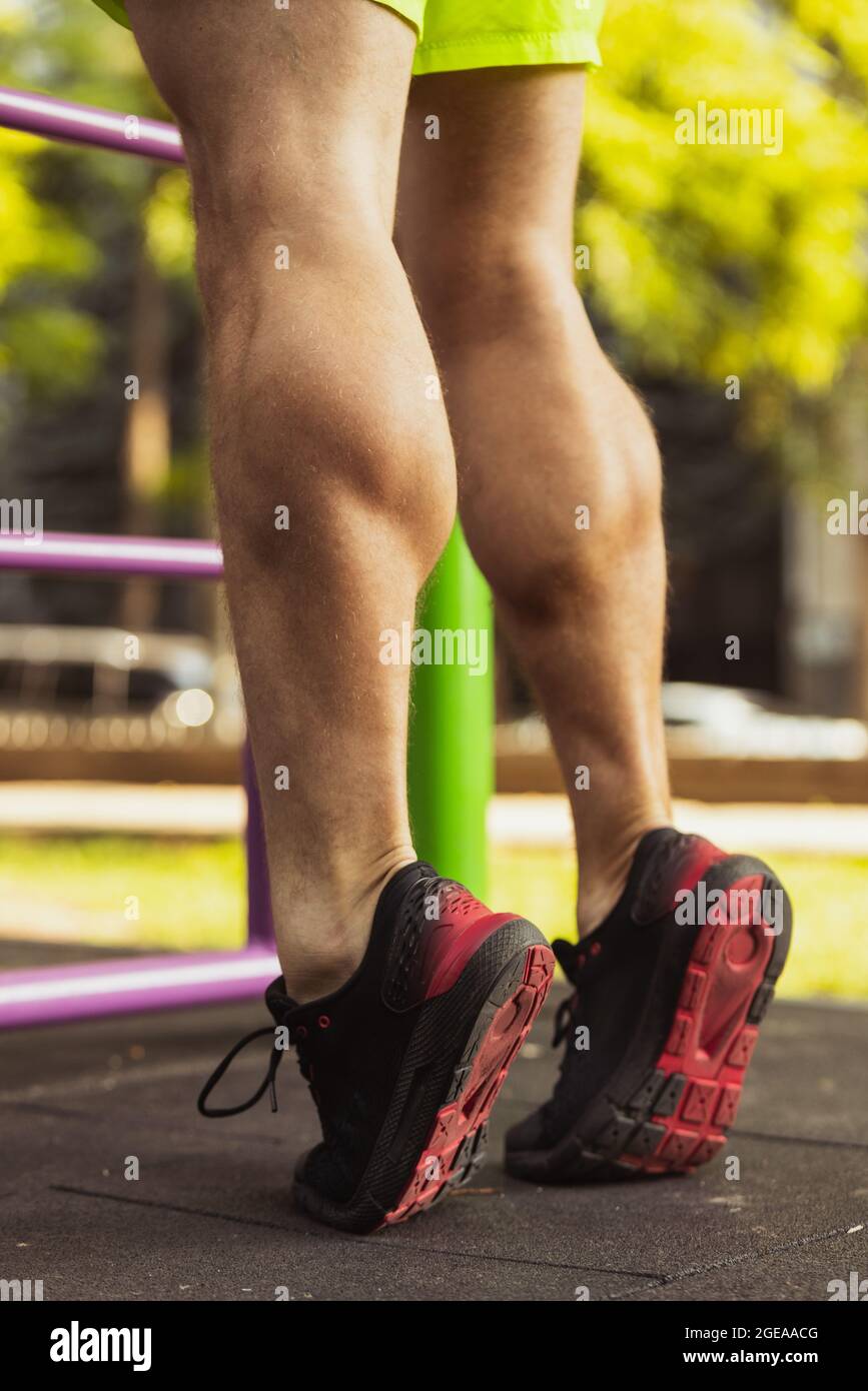 Cropped image of male muscular legs, feet in sportshoes standing on ...