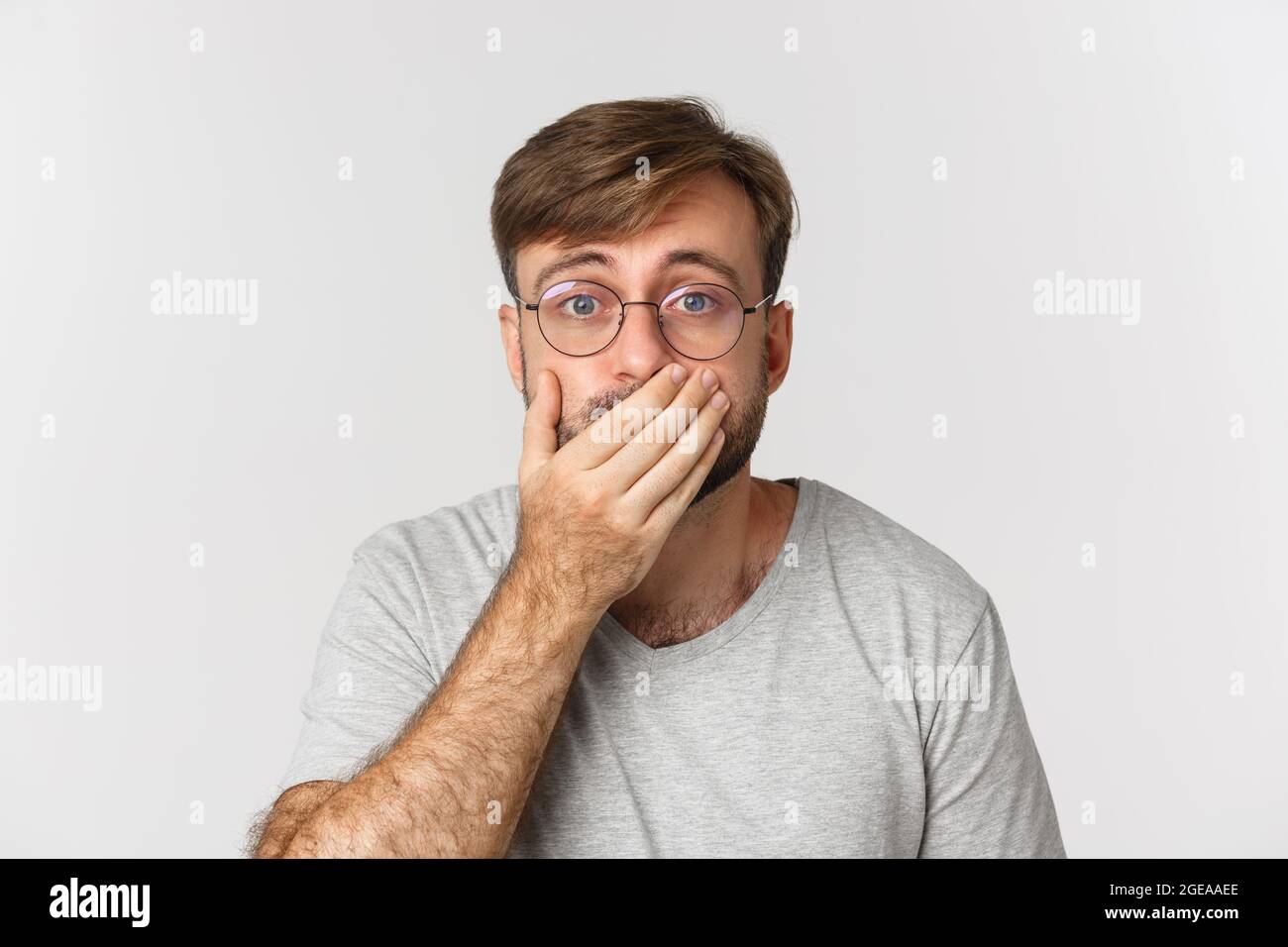 Close-up of shocked and worried man in glasses, gasping and cover mouth ...