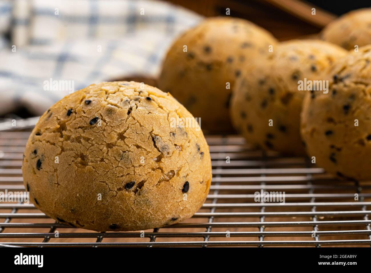Closeup view freshly baked homemade sesame mochi bun on metal cooling ...
