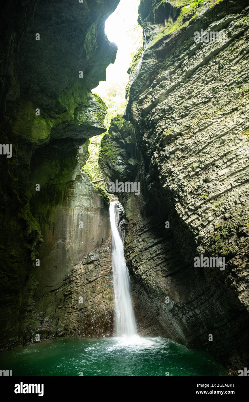 Crystal clear waterfall in a limestone cave flooded with sunlight and ...