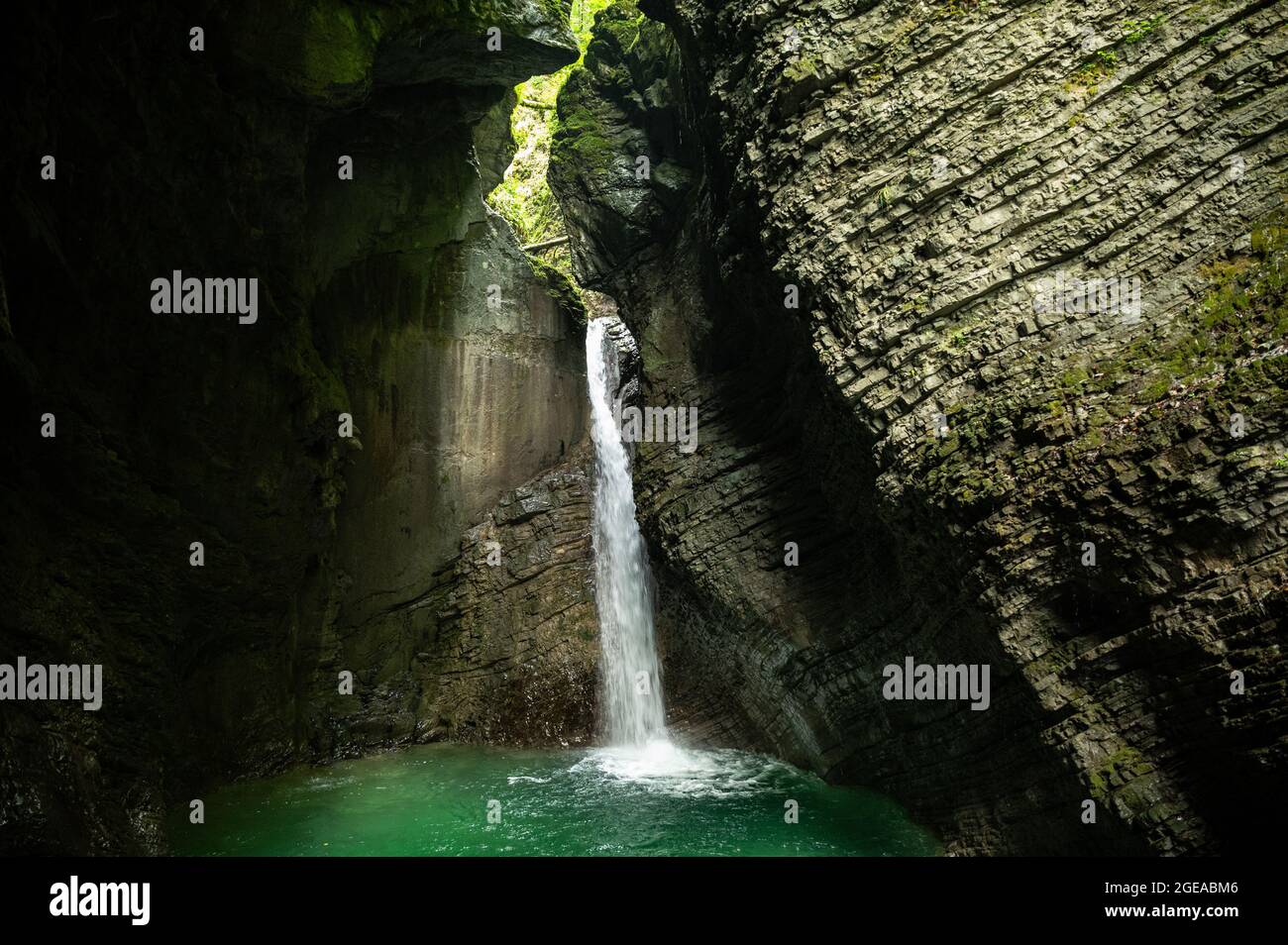 Crystal clear waterfall in a limestone cave flooded with sunlight and ...