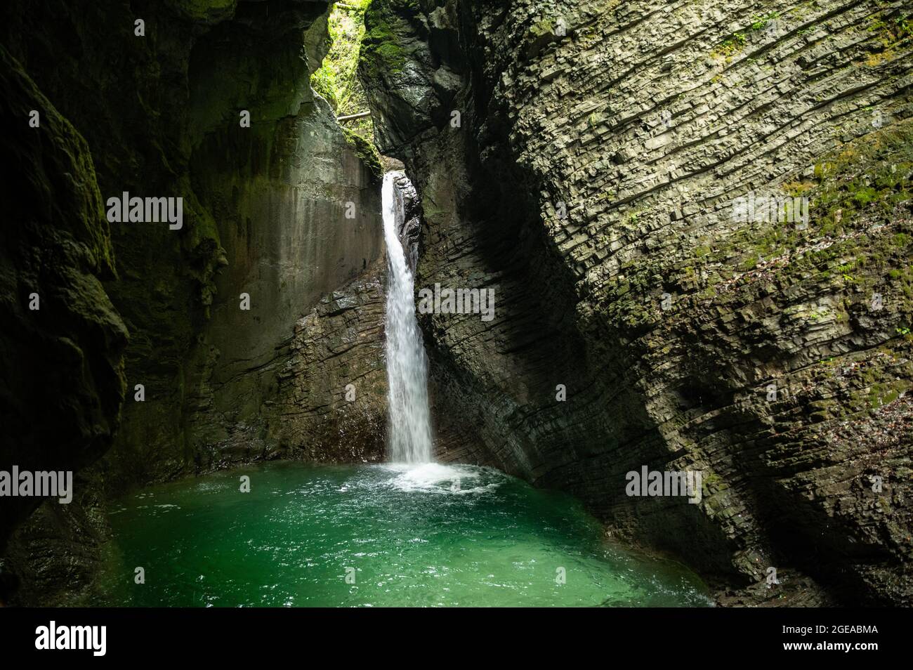 Crystal clear waterfall in a limestone cave flooded with sunlight and ...