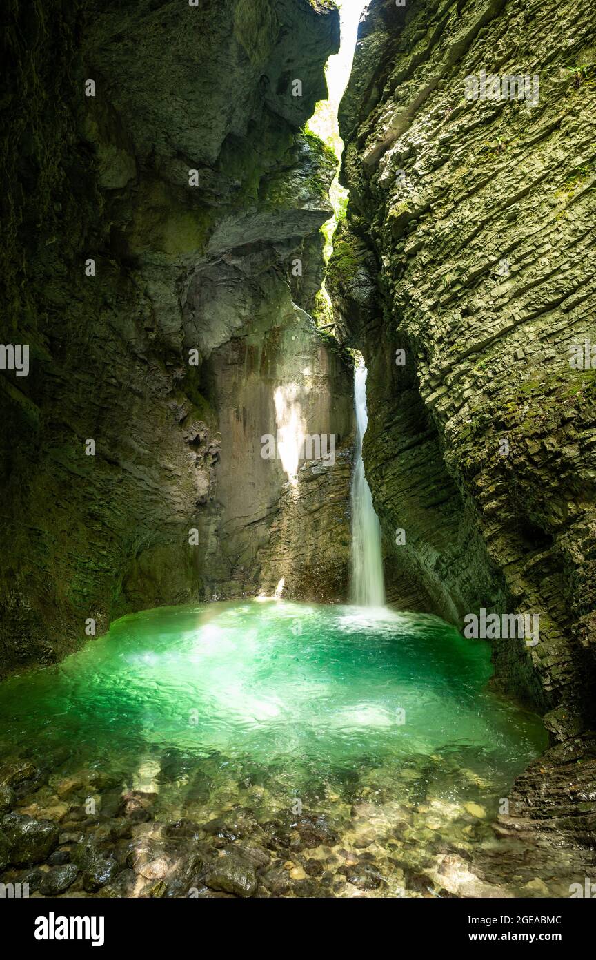 Crystal clear waterfall in a limestone cave flooded with sunlight and ...
