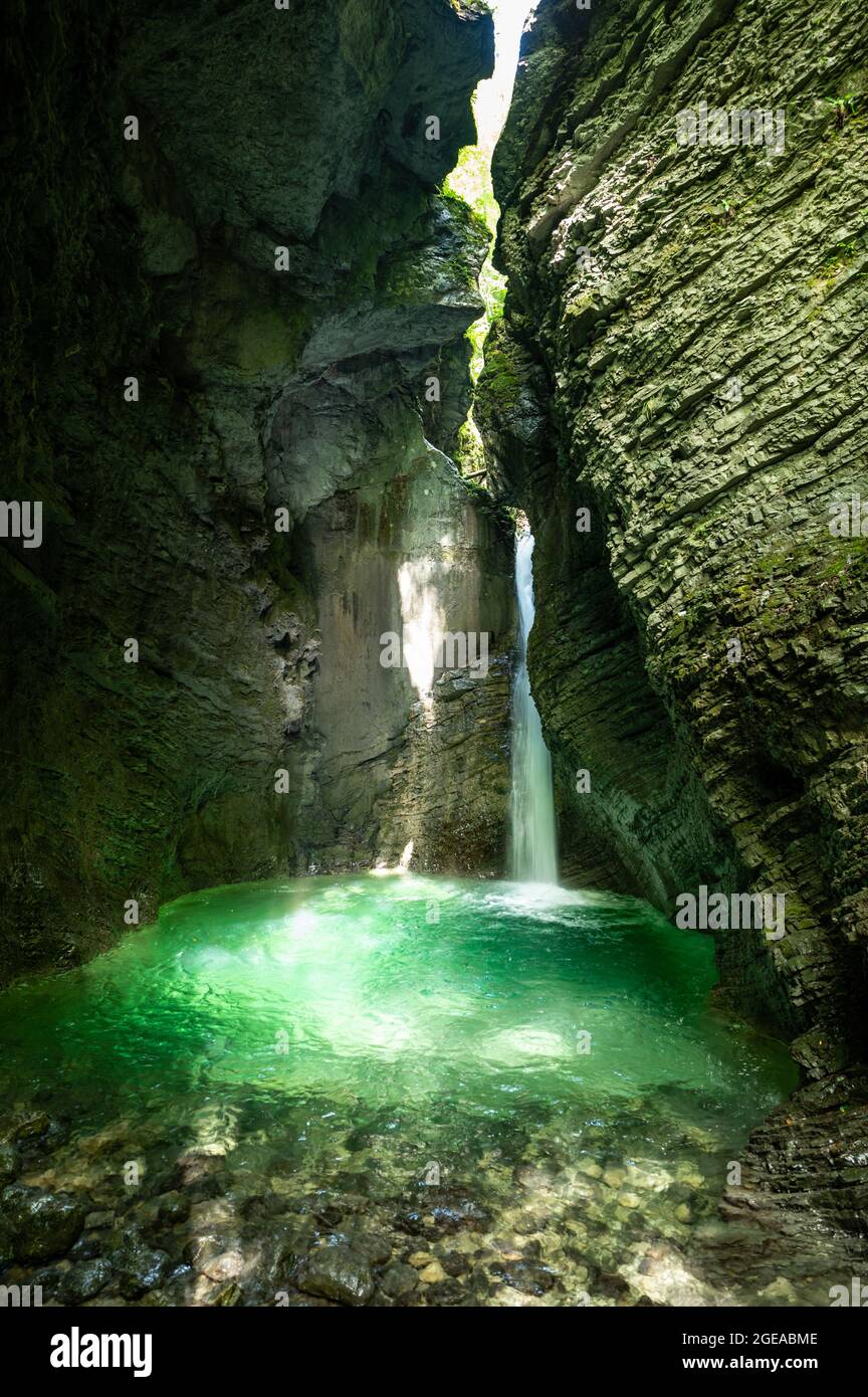 Crystal clear waterfall in a limestone cave flooded with sunlight and ...