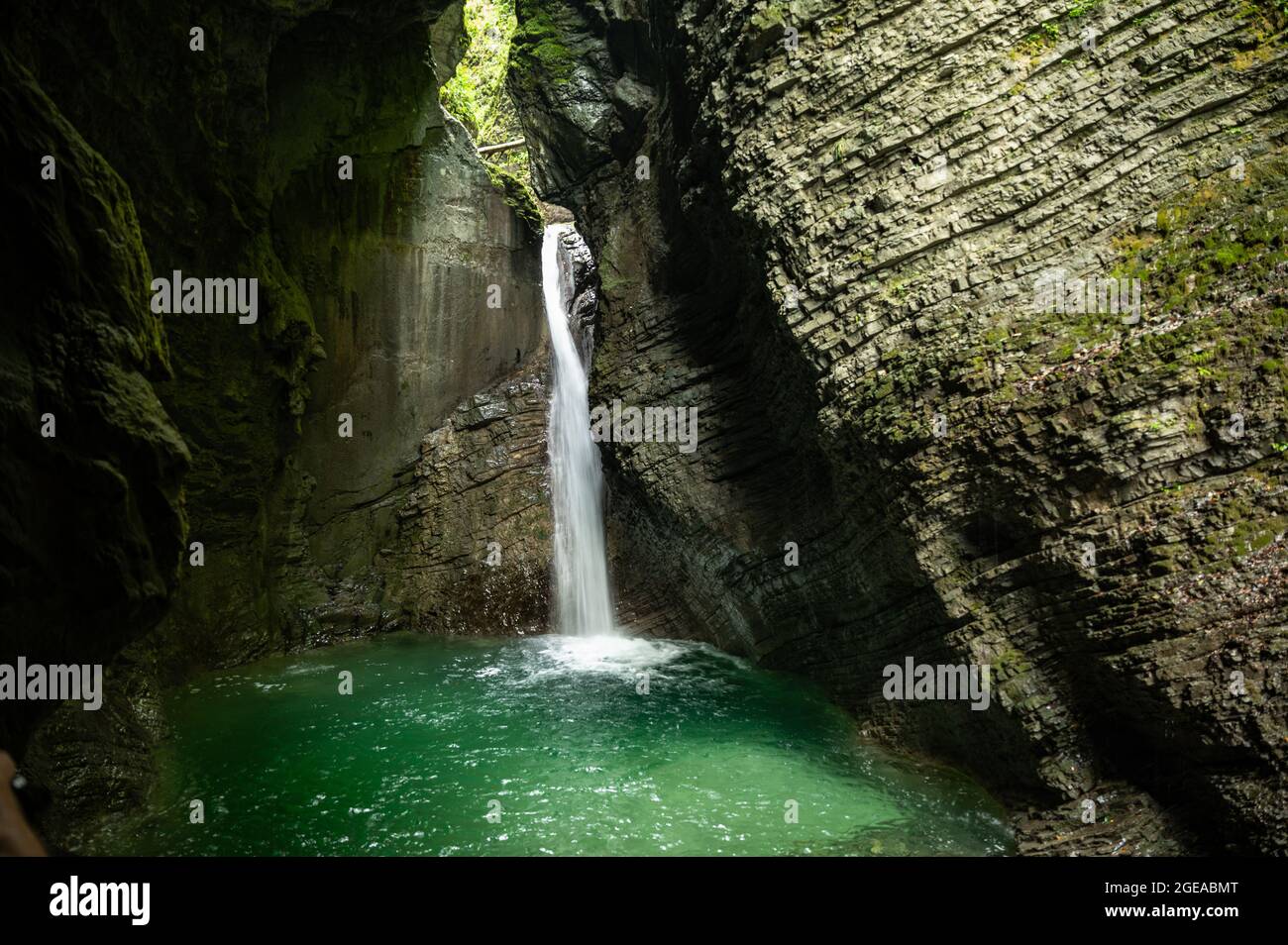 Crystal clear waterfall in a limestone cave flooded with sunlight and ...