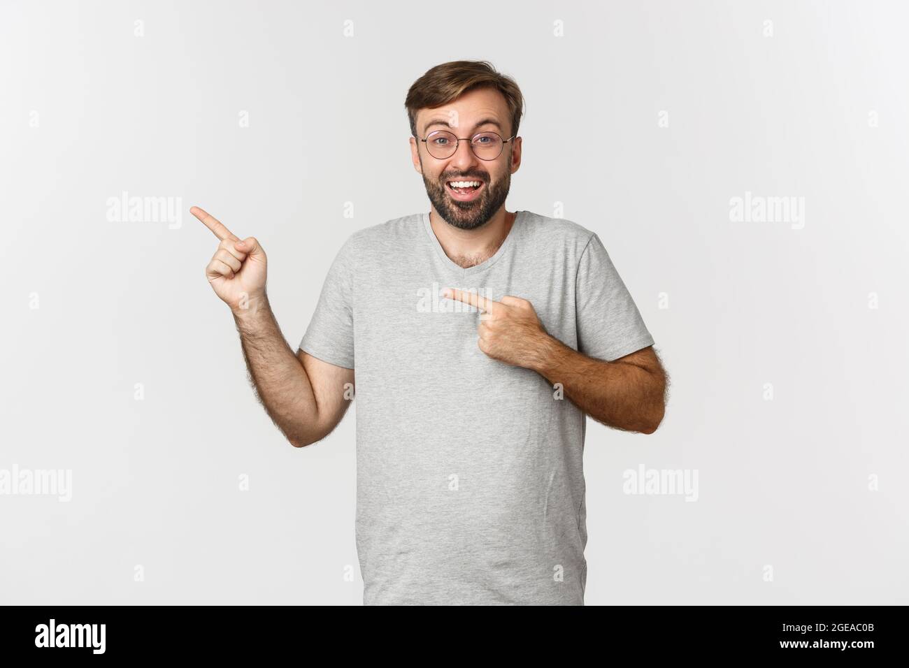 Excited bearded man smiling, pointing fingers at upper left corner ...