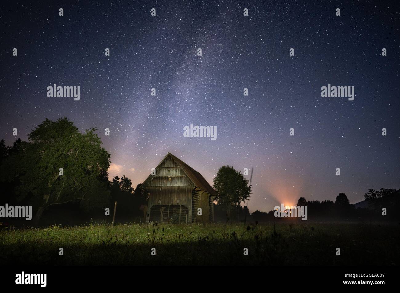 Milky way over traditional Slovenian barn house (hayloft) in the night ...
