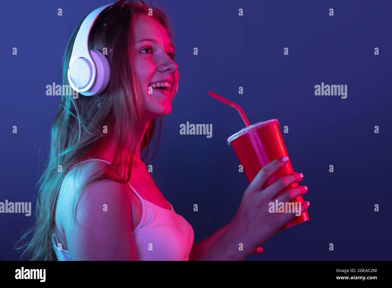 Portrait of young smiling girl isolated on dark blue studio background ...