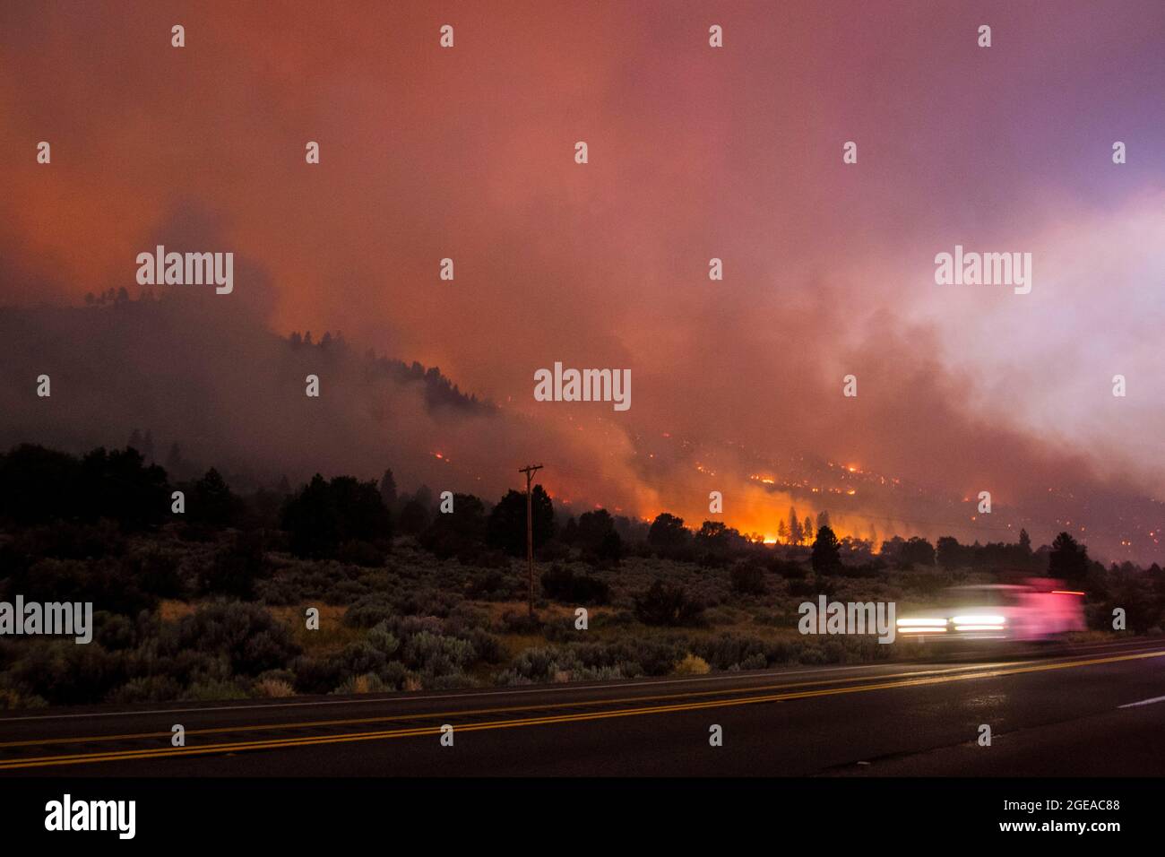 United States. 17th Aug, 2021. Cars on 395 highway pass by flames and ...