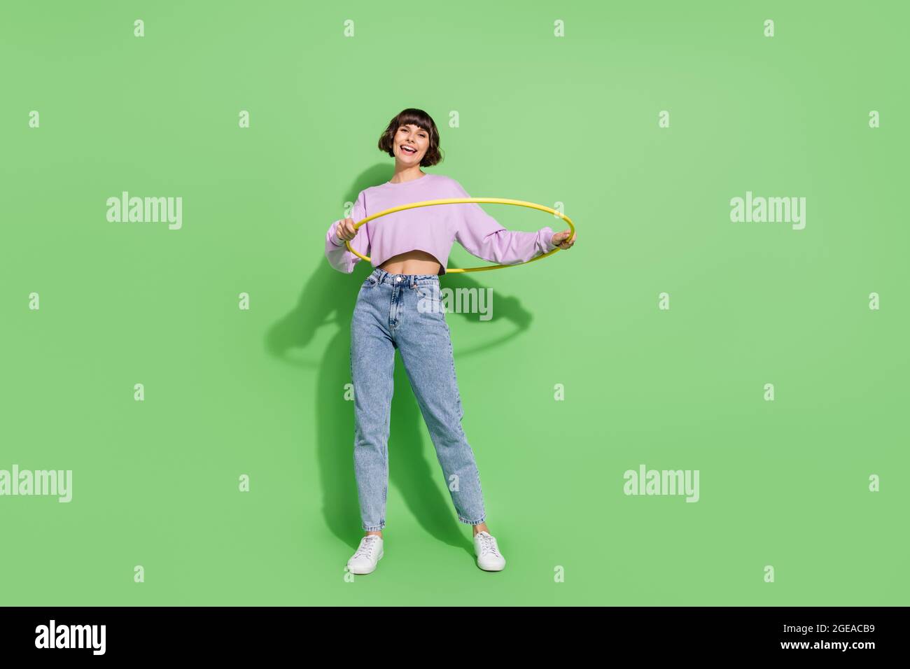 Full length body size view of attractive cheerful girl spinning hula ...