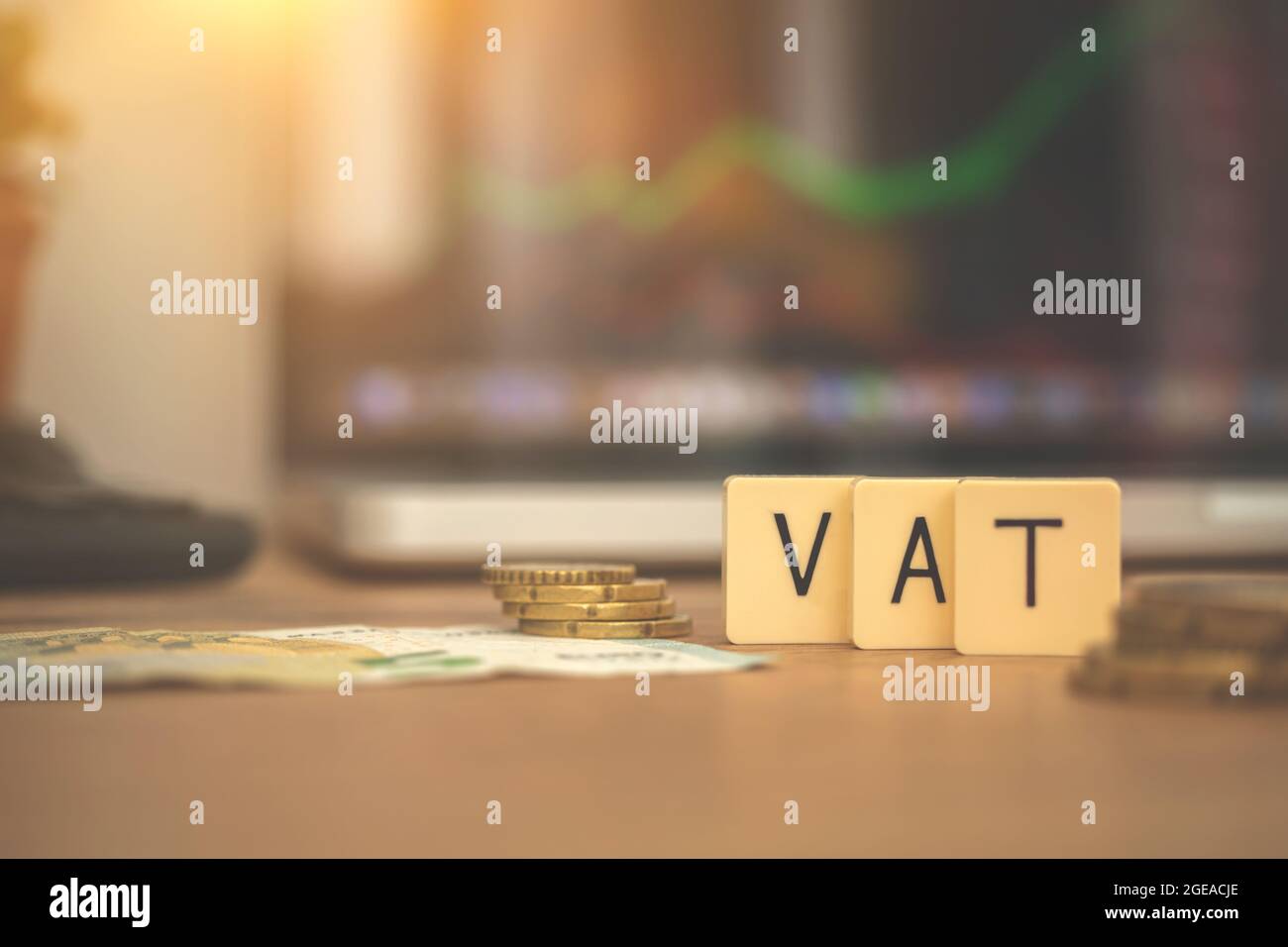 VAT concept. Word VAT and coins on stock market or forex trading graphs ...