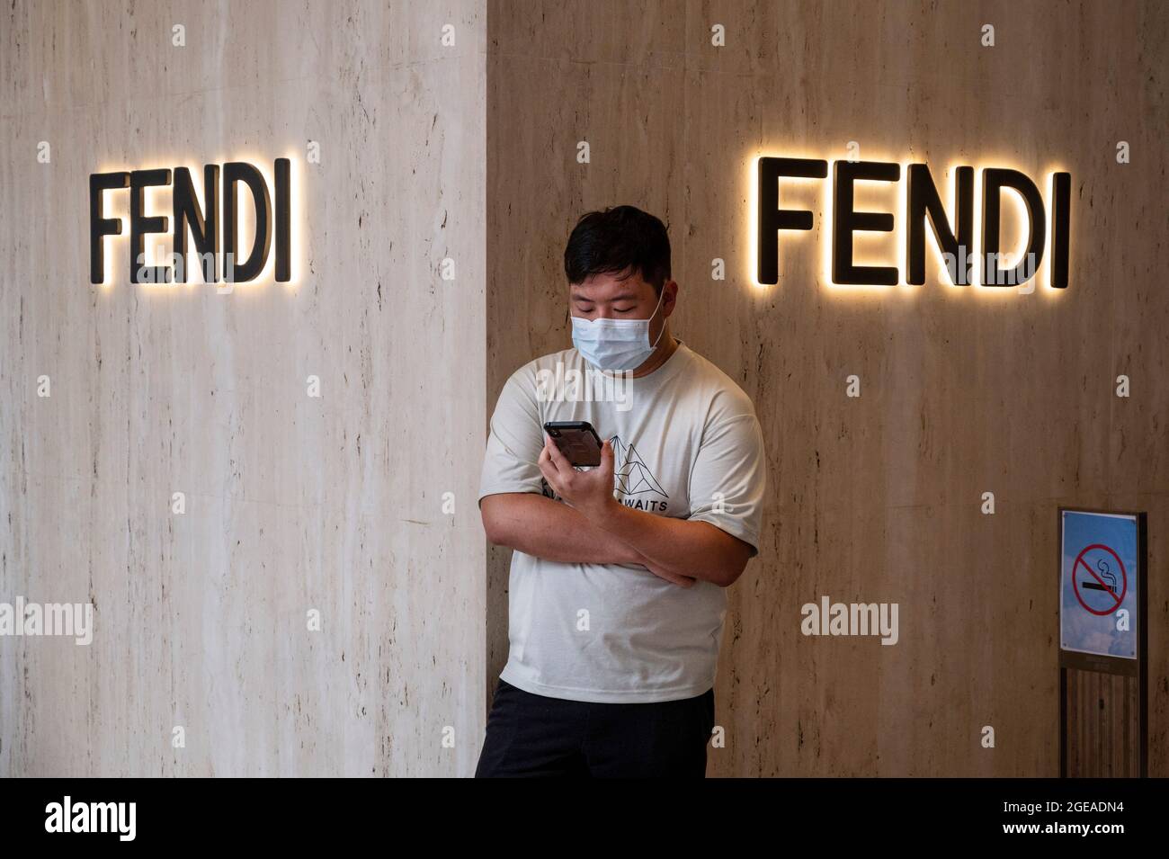 A man wearing a face mask uses his smartphone outside the Italian ...