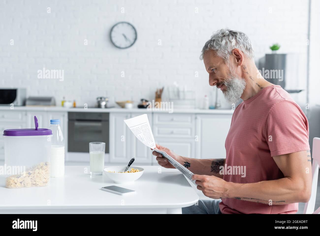 Side view of mature man reading news near smartphone and breakfast ...