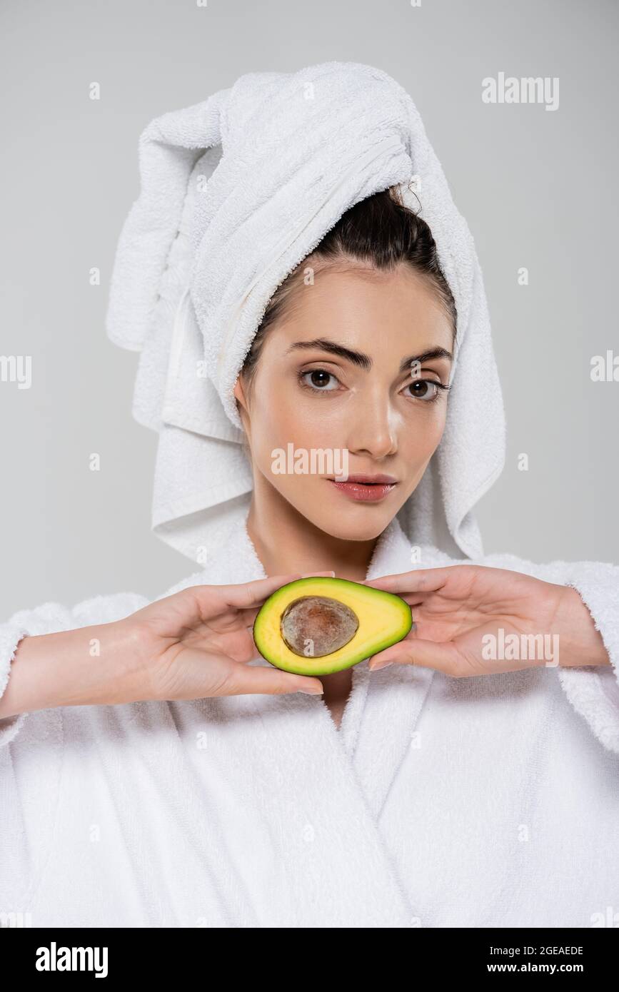 young woman in bathrobe holding half of avocado isolated on grey Stock ...