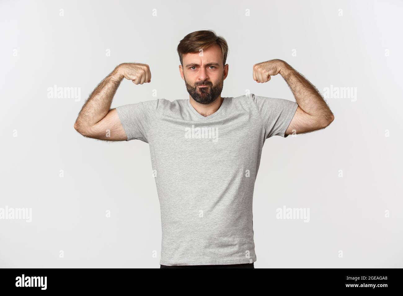 Portrait of confident bearded man flexing biceps, showing his muscles ...