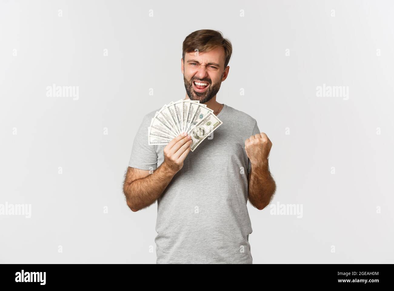 Pleased smiling man with beard, wearing gray t-shirt, rejoicing and ...
