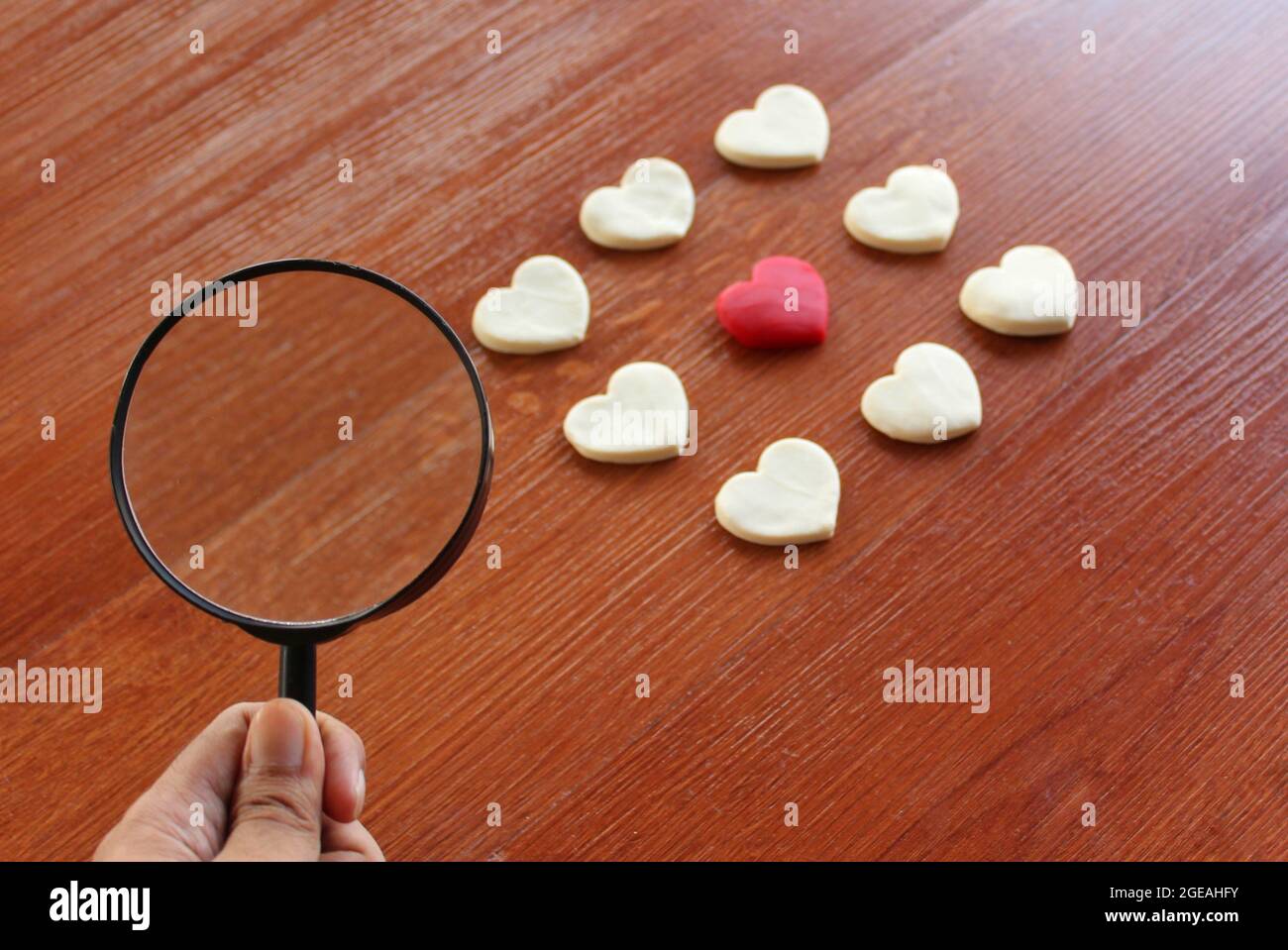 Magnifying glass, red heart and white heart. Finding true love ...