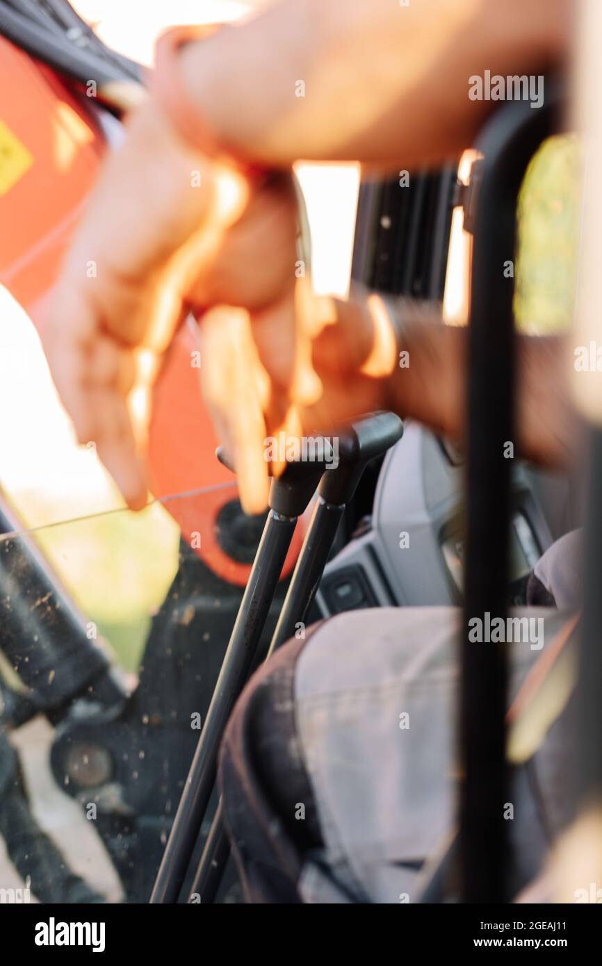 Detail of a workers hands on an excavator cabin on a construction site ...