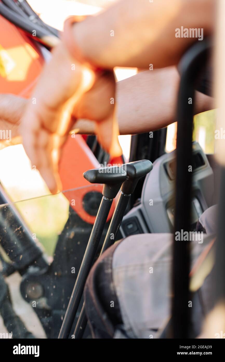 Detail of a workers hands on an excavator cabin on a construction site ...