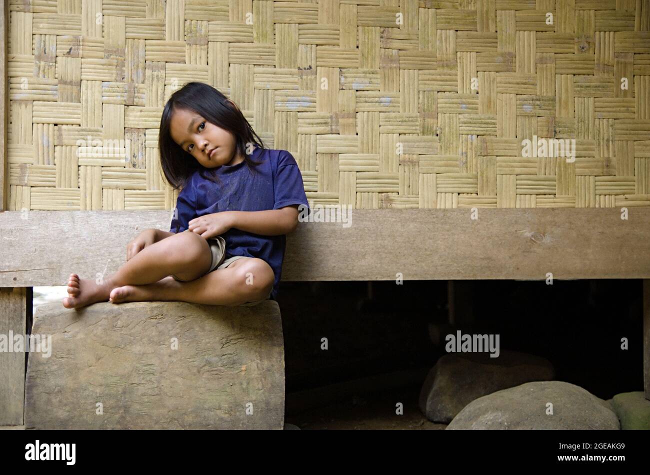 A cute Baduy girl sits beside her house. Baduy is a tribe in Banten ...