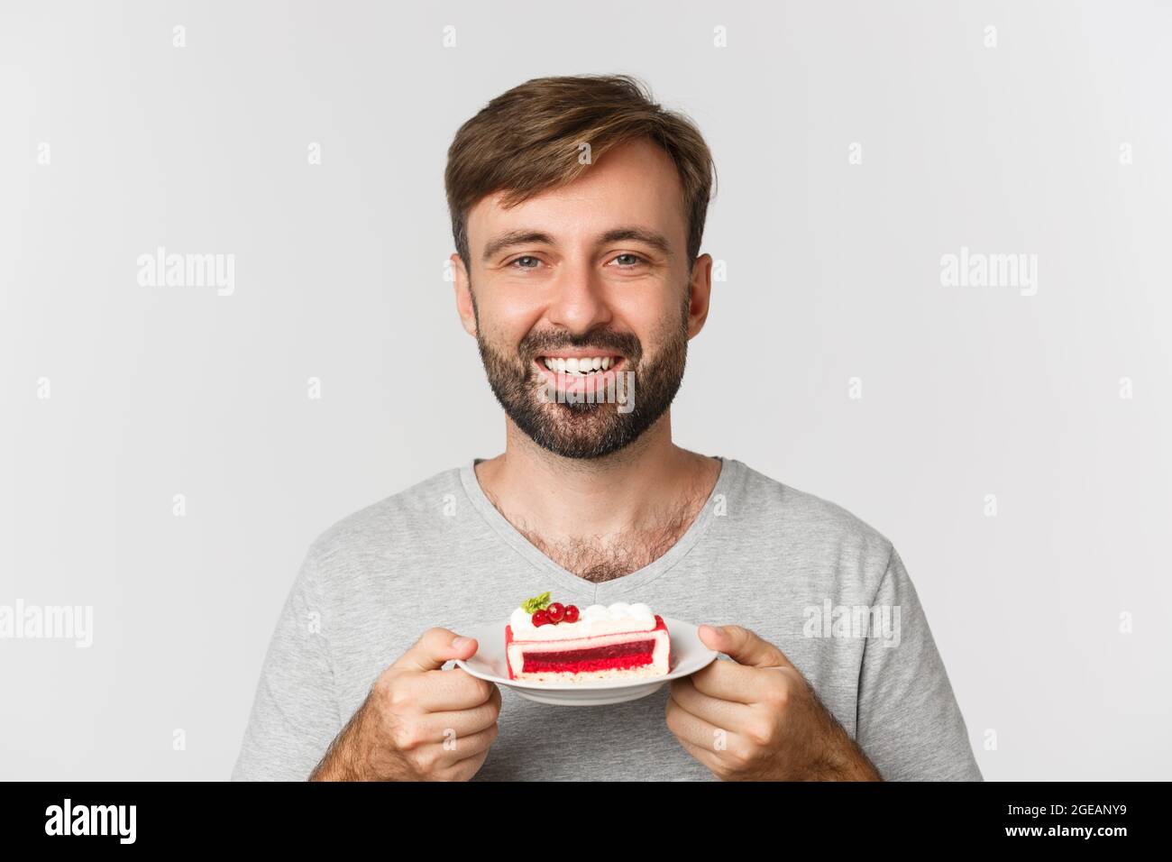 Close-up of handsome smiling man holding cake, standing over white ...