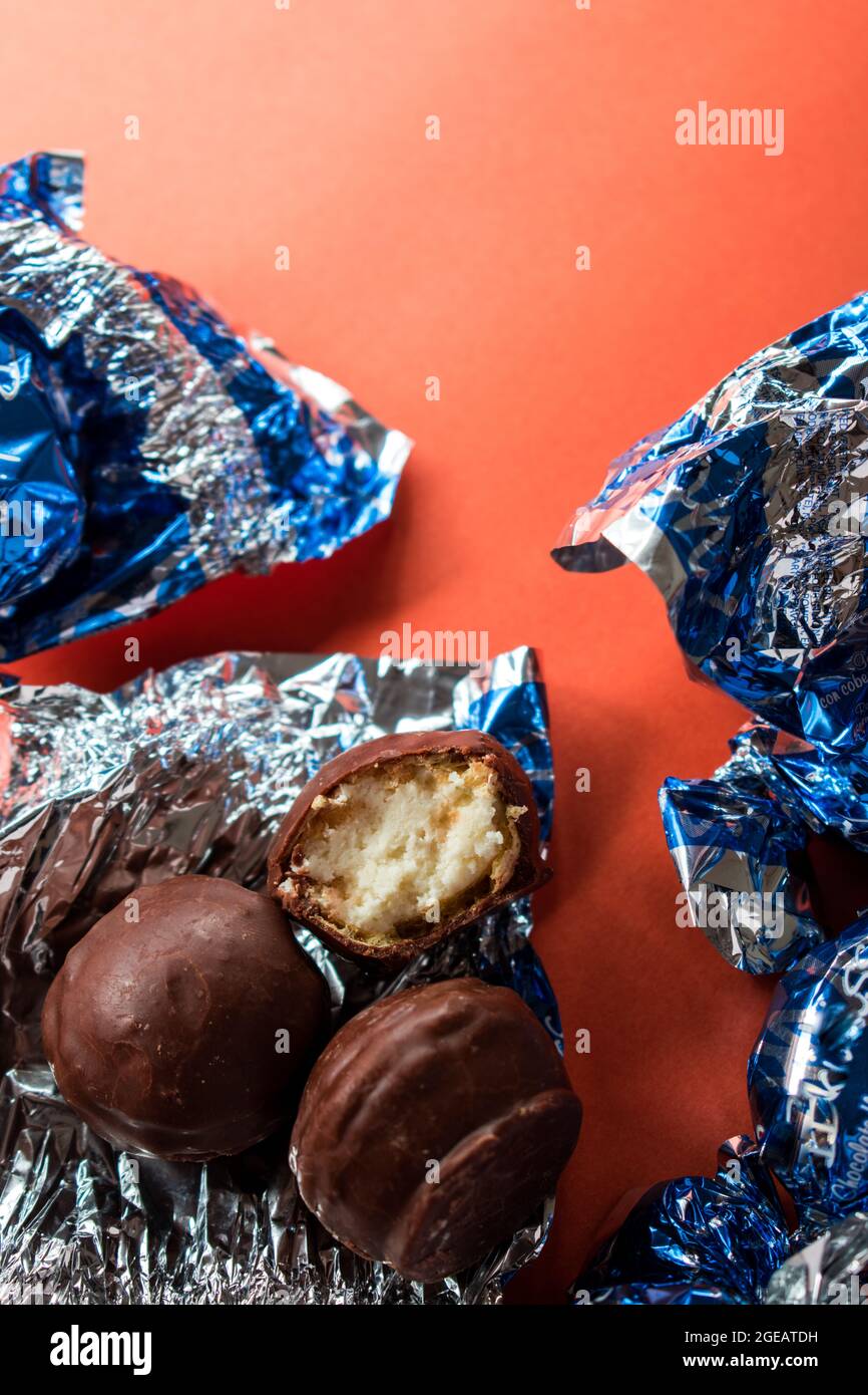 Some chocolates and some different colorful wrappers on orange surface ...