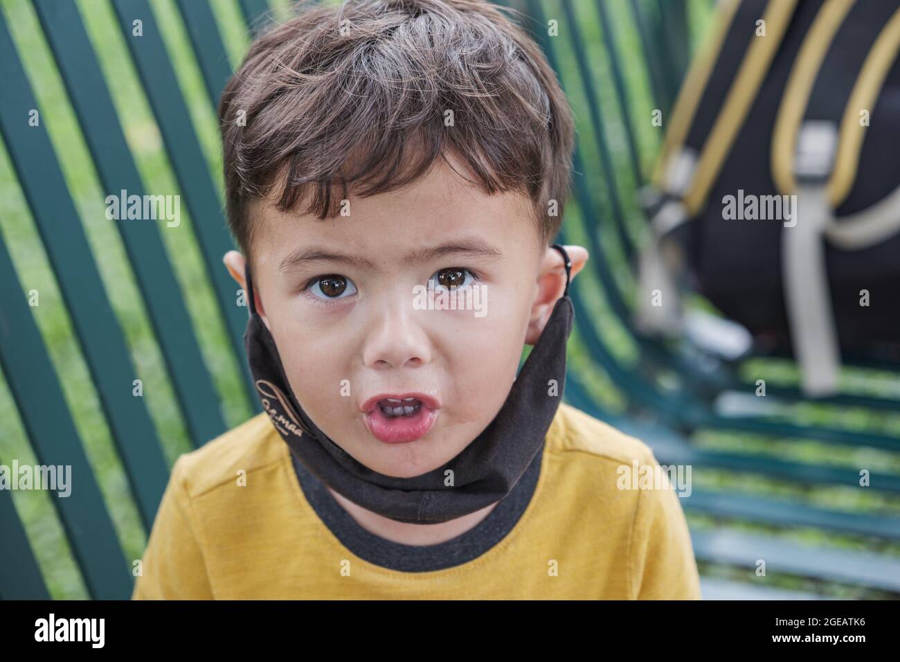 Cute young boy with face mask hanging below his chin Stock Photo - Alamy
