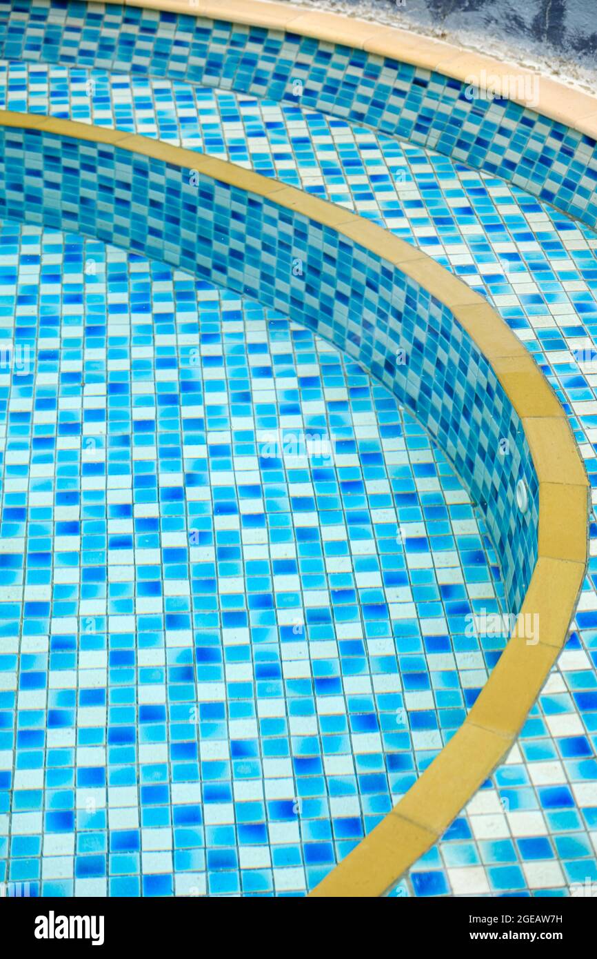 clear water in a still small swimming pool with blue and white tiles ...