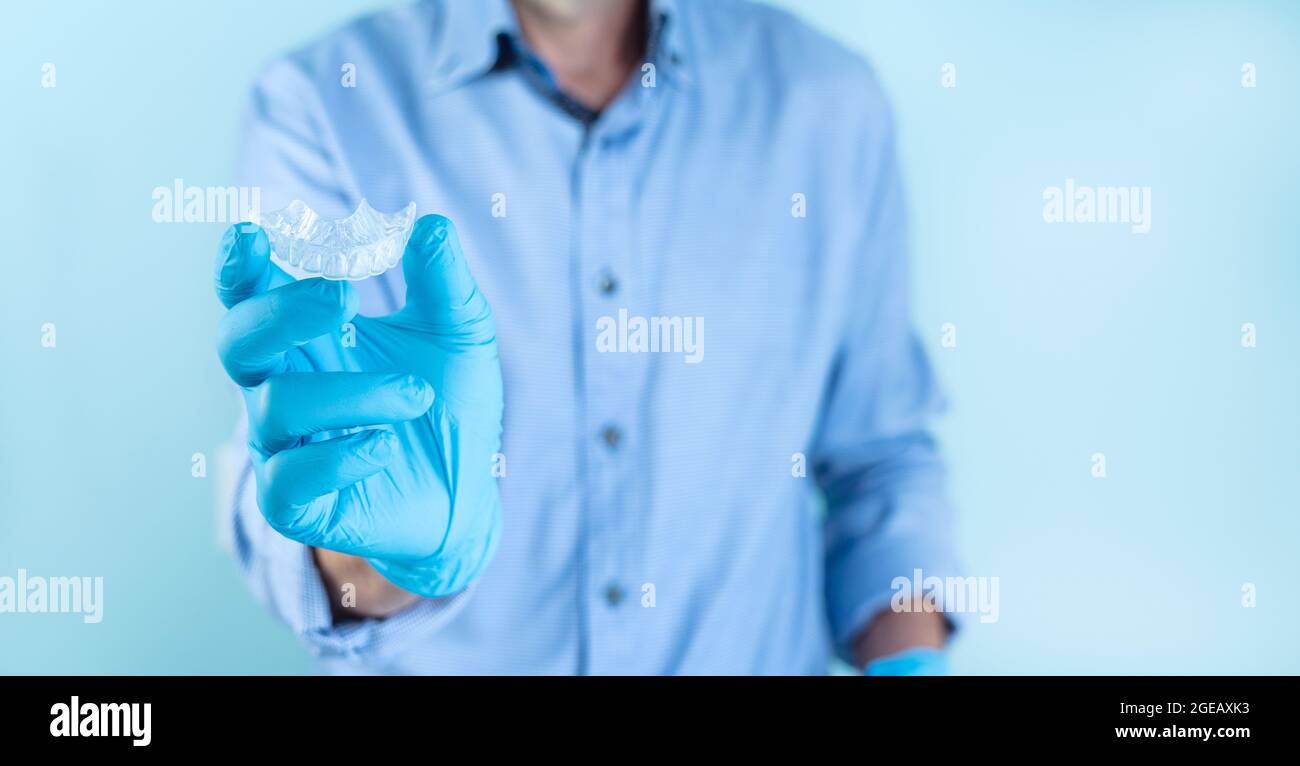 Dentist in gloves and blue shirt showing a clear dental splint. Copy ...