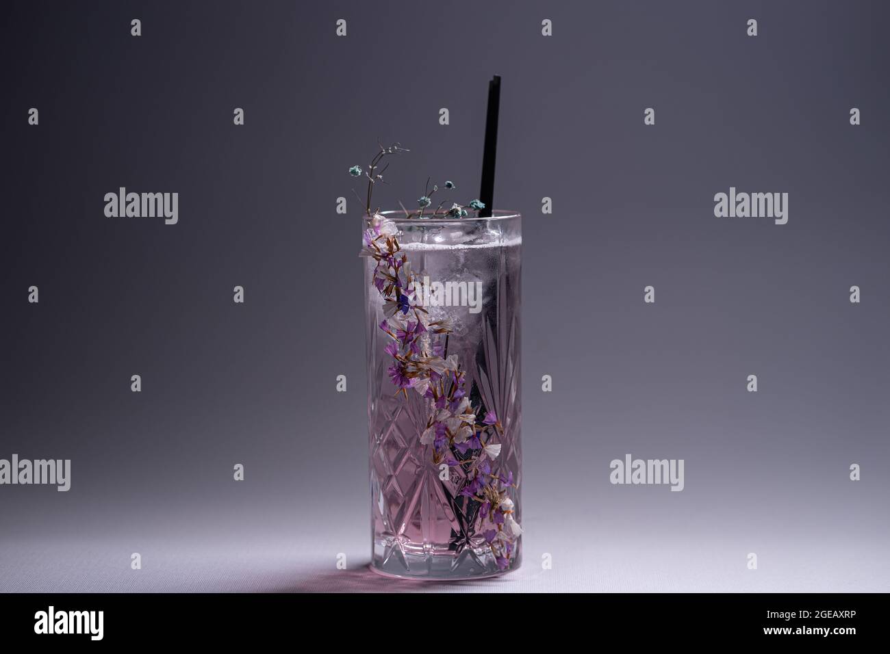luxury violet fizz cocktail drink with flower decoration on grey ...