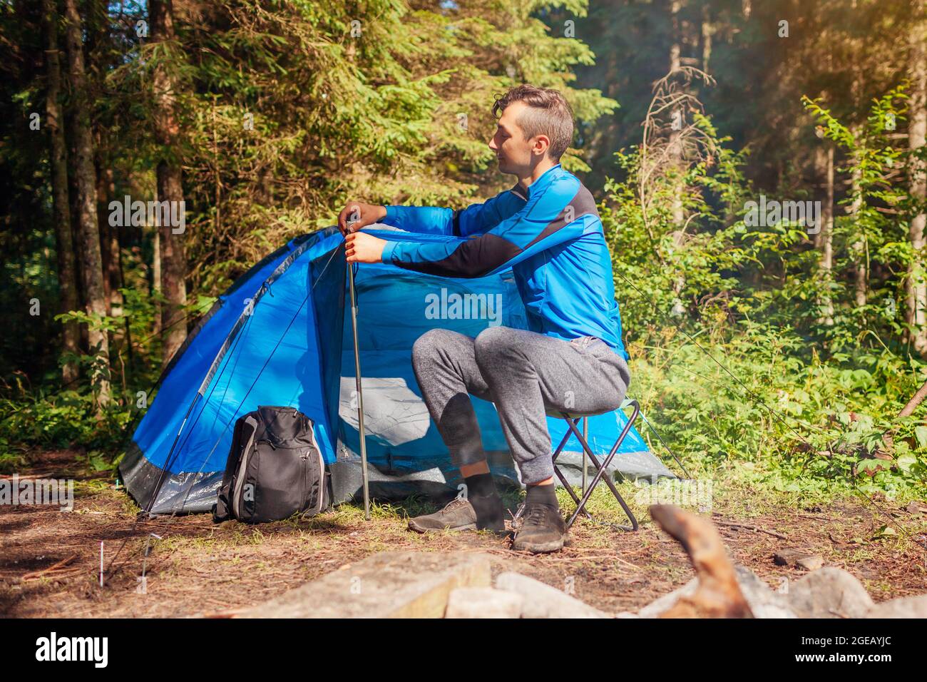 Young man setting up tent on camping trip in forest. Summer camping ...