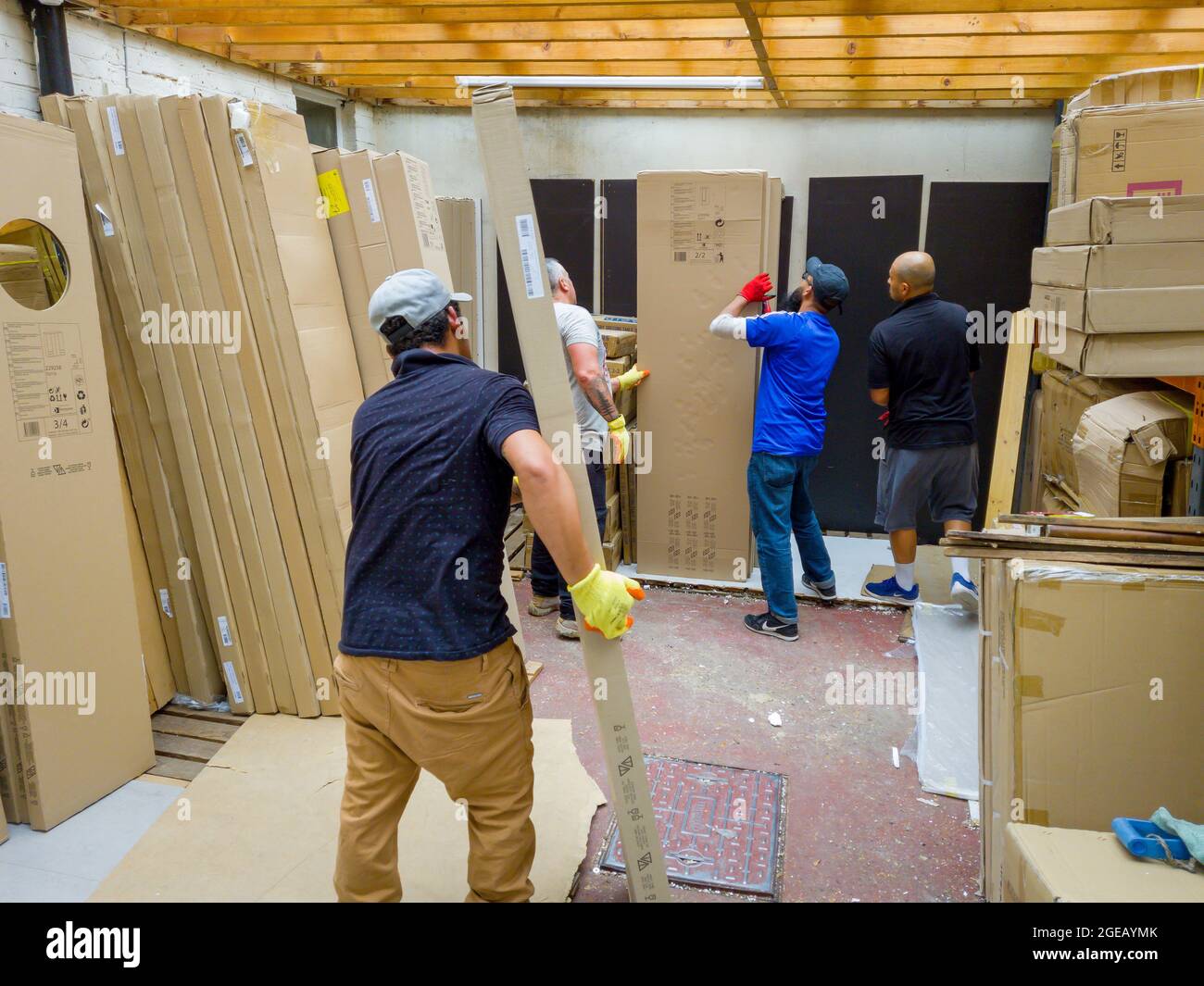London. UK- 08.13.2021: workers carrying heavy packages into a ...