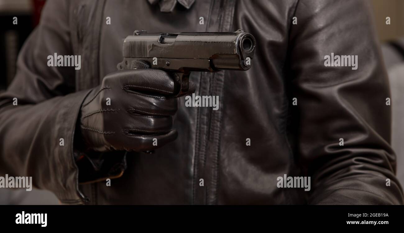 Pistol in gloved hand. Killer, murderer wearing black leather jacket ...