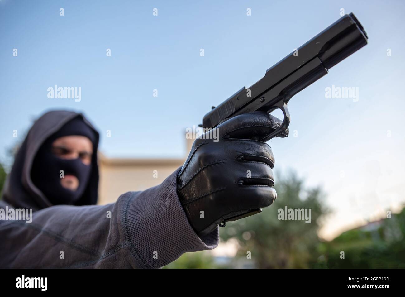 Man aiming with a pistol, nature outdoors background, closeup view ...