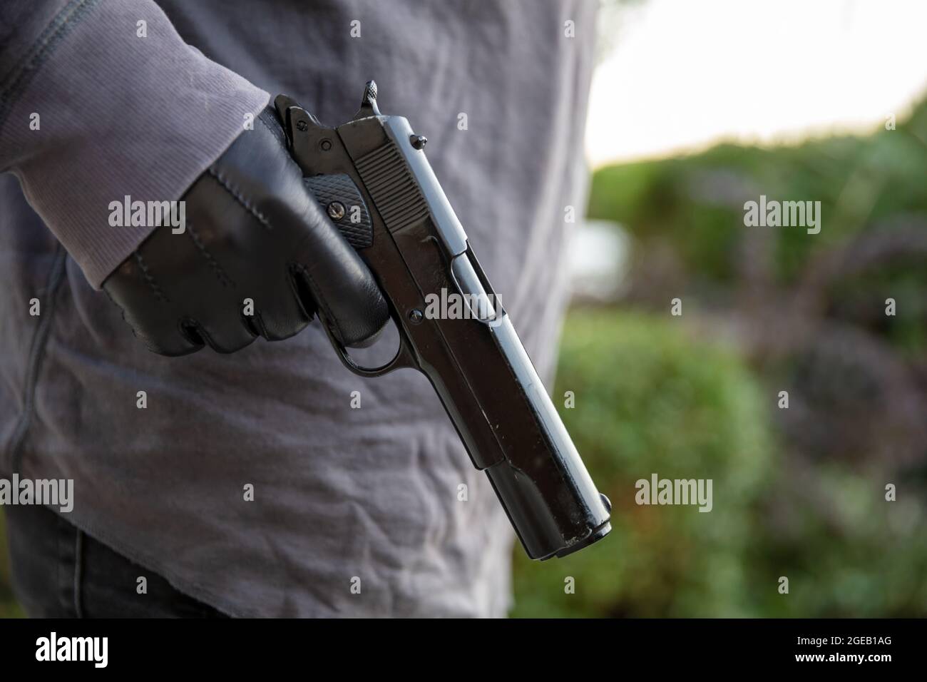 Armed man moving, holding a pistol in his gloved hand, blur outdoor ...