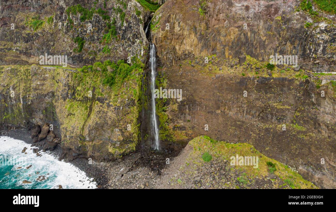 Waterfall falling into ocean from volcanic cliffs Stock Photo - Alamy