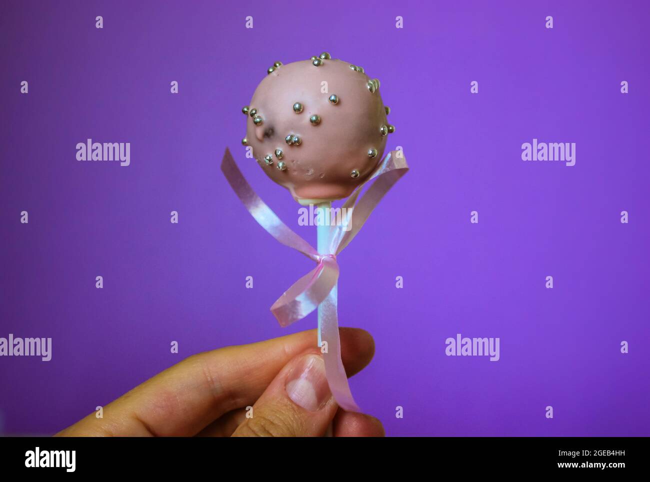 Pink chocolate cake pops with strawberry flavour on a purple background ...