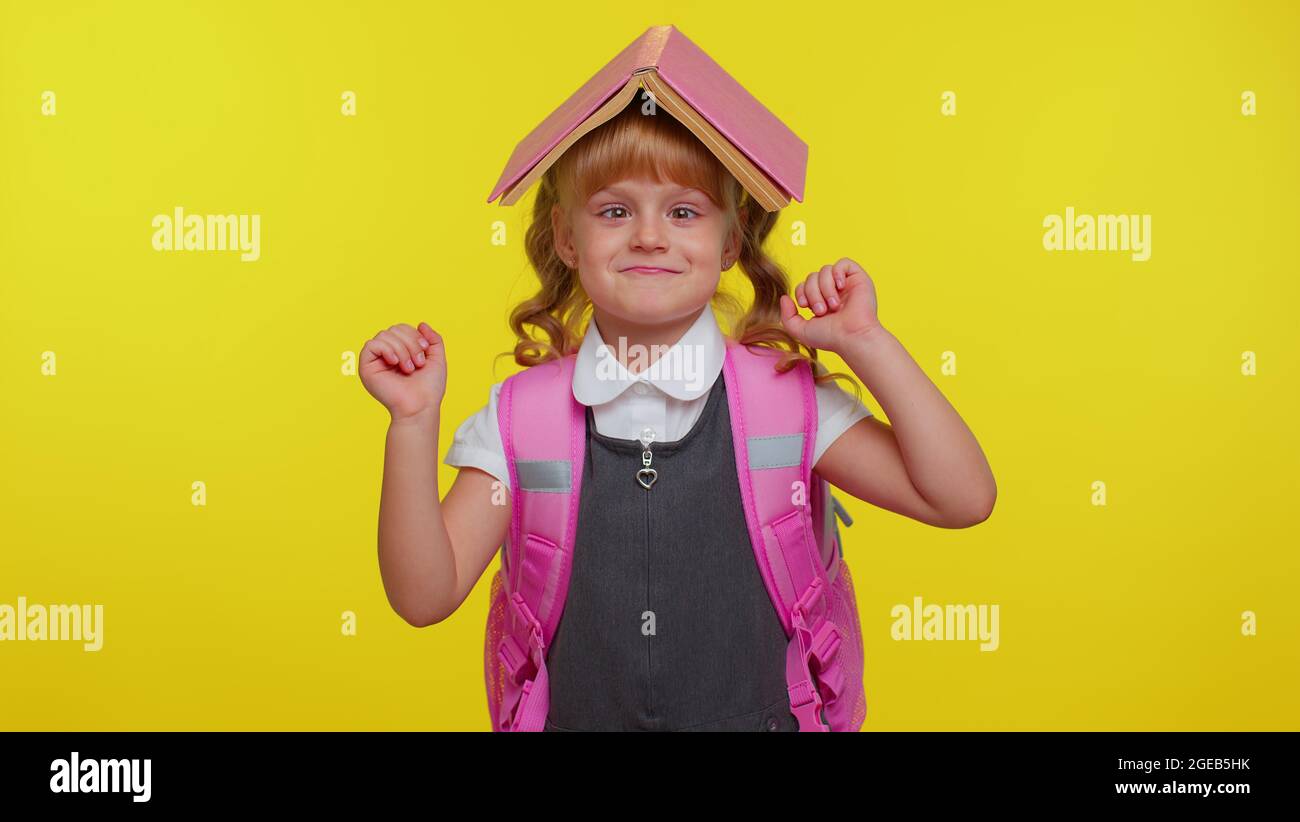Cheerful cute happy funny schoolgirl kid with book on head, making ...