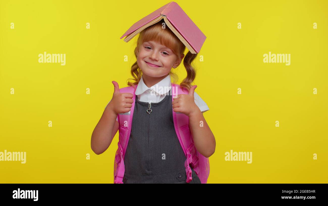 Smiling schoolgirl reading book, making playful silly facial ...