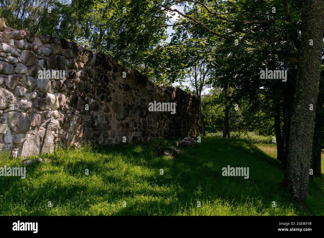 Medieval castle mound wall made of many stones. It is obscured by ...