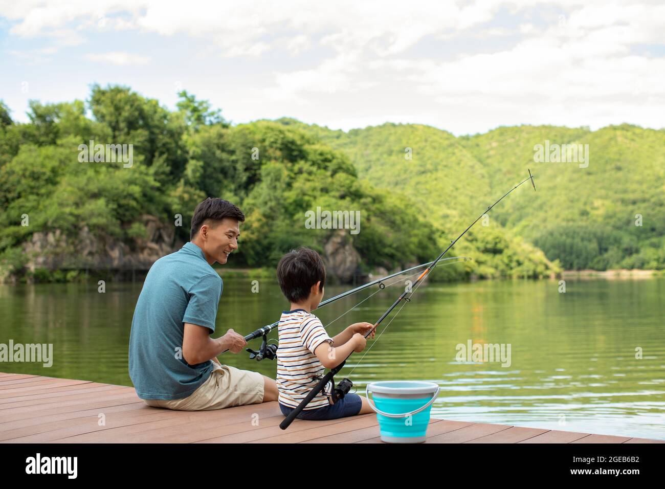 Happy Chinese father and son fishing by the river Stock Photo - Alamy