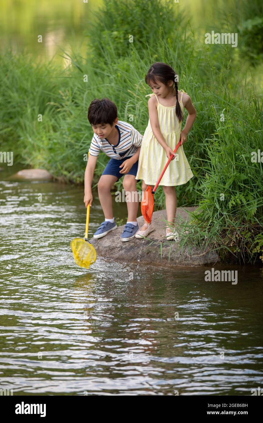 Chinese children playing with fishing net by the river Stock Photo - Alamy