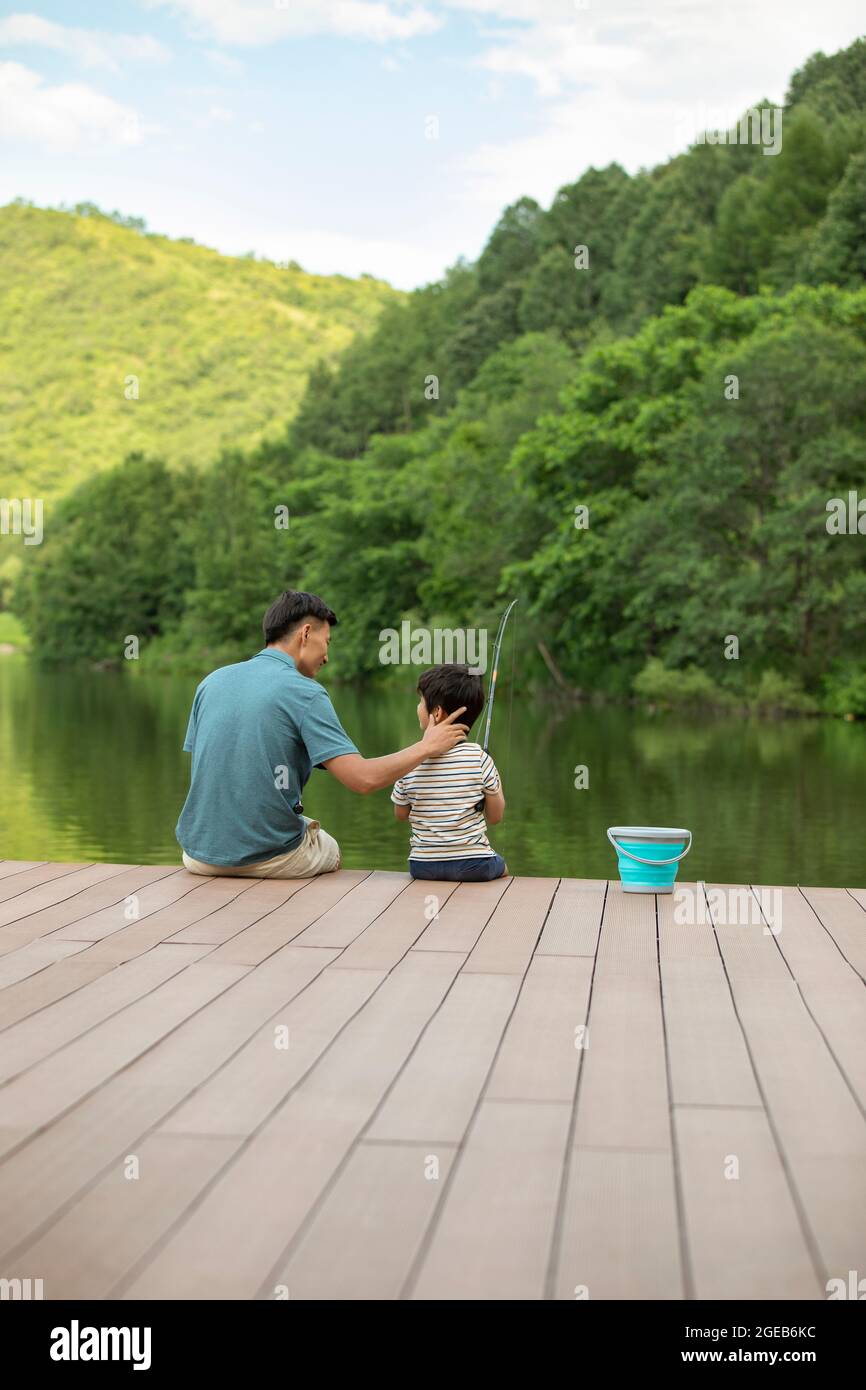 Happy Chinese father and son fishing by the river Stock Photo - Alamy