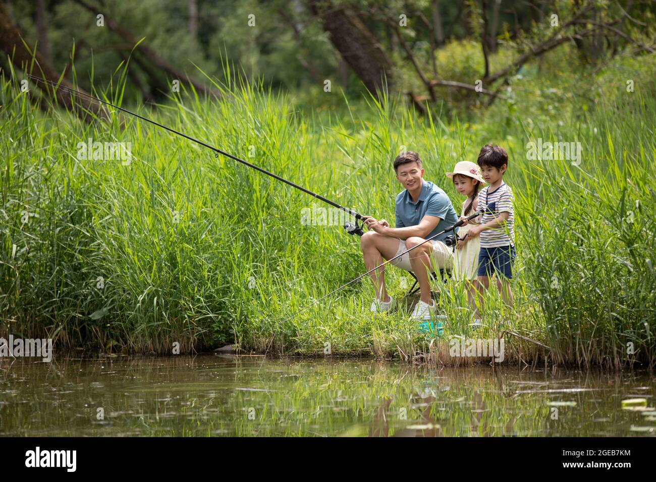 Happy young Chinese family fishing by the river Stock Photo - Alamy