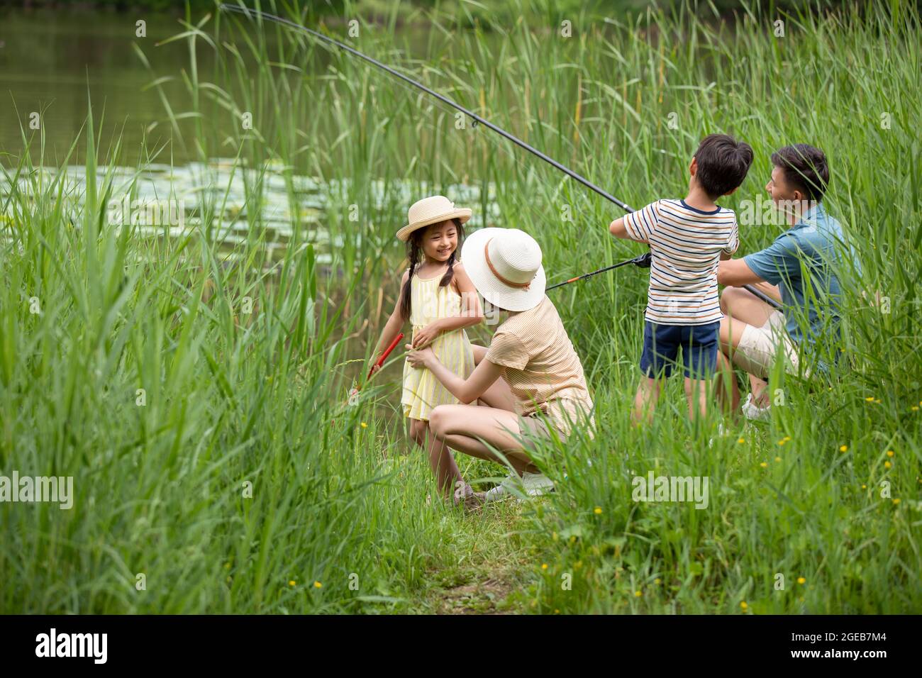 Happy young Chinese family fishing by the river Stock Photo - Alamy